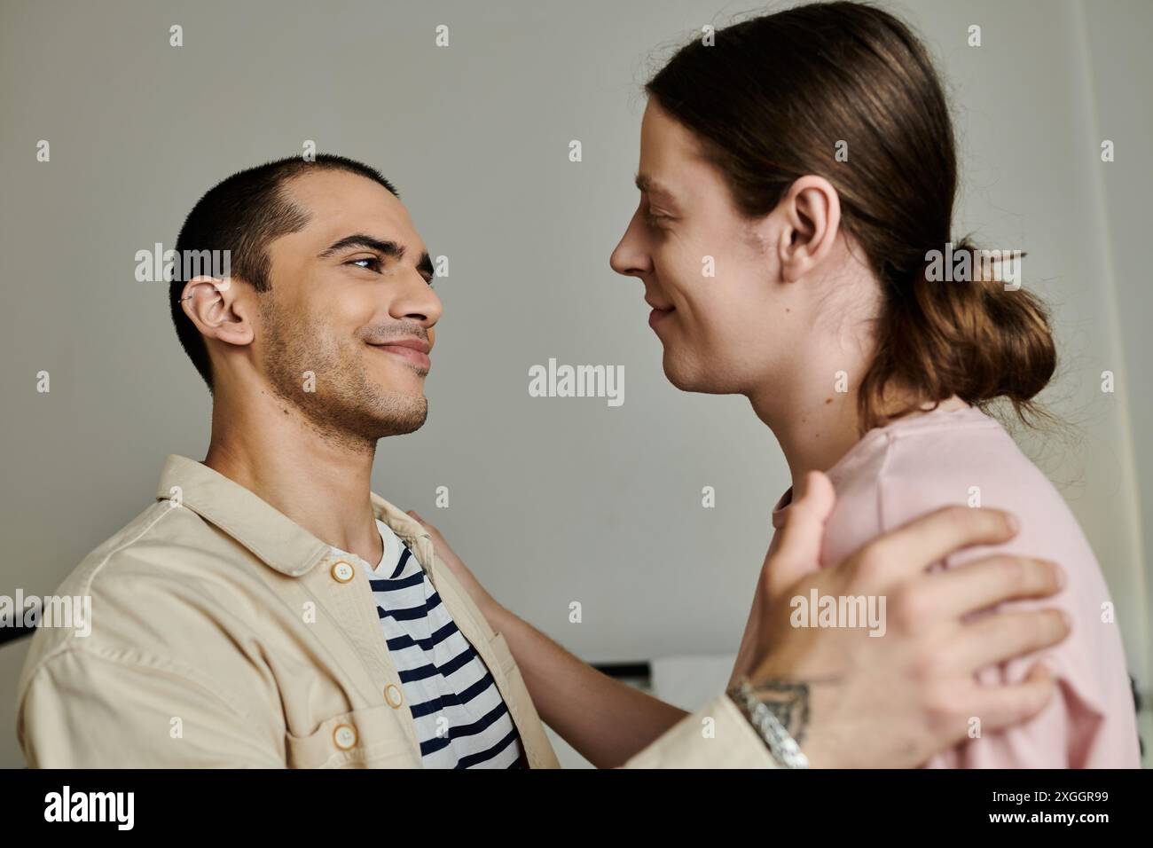 Two young men in casual attire look lovingly at each other in a modern ...