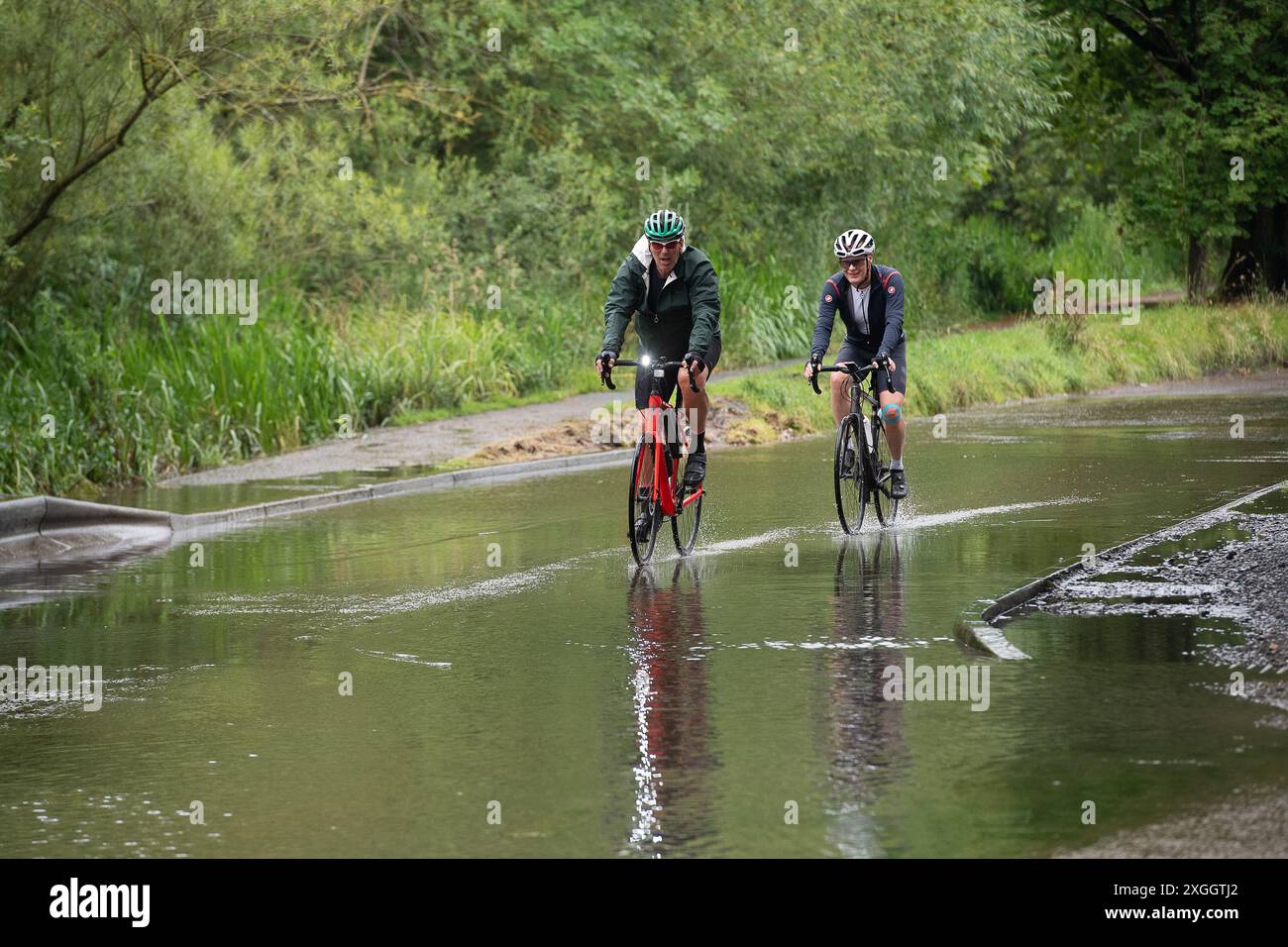 Chesham, UK. 9th July, 2024. Cyclists move gingerly through floodwater ...