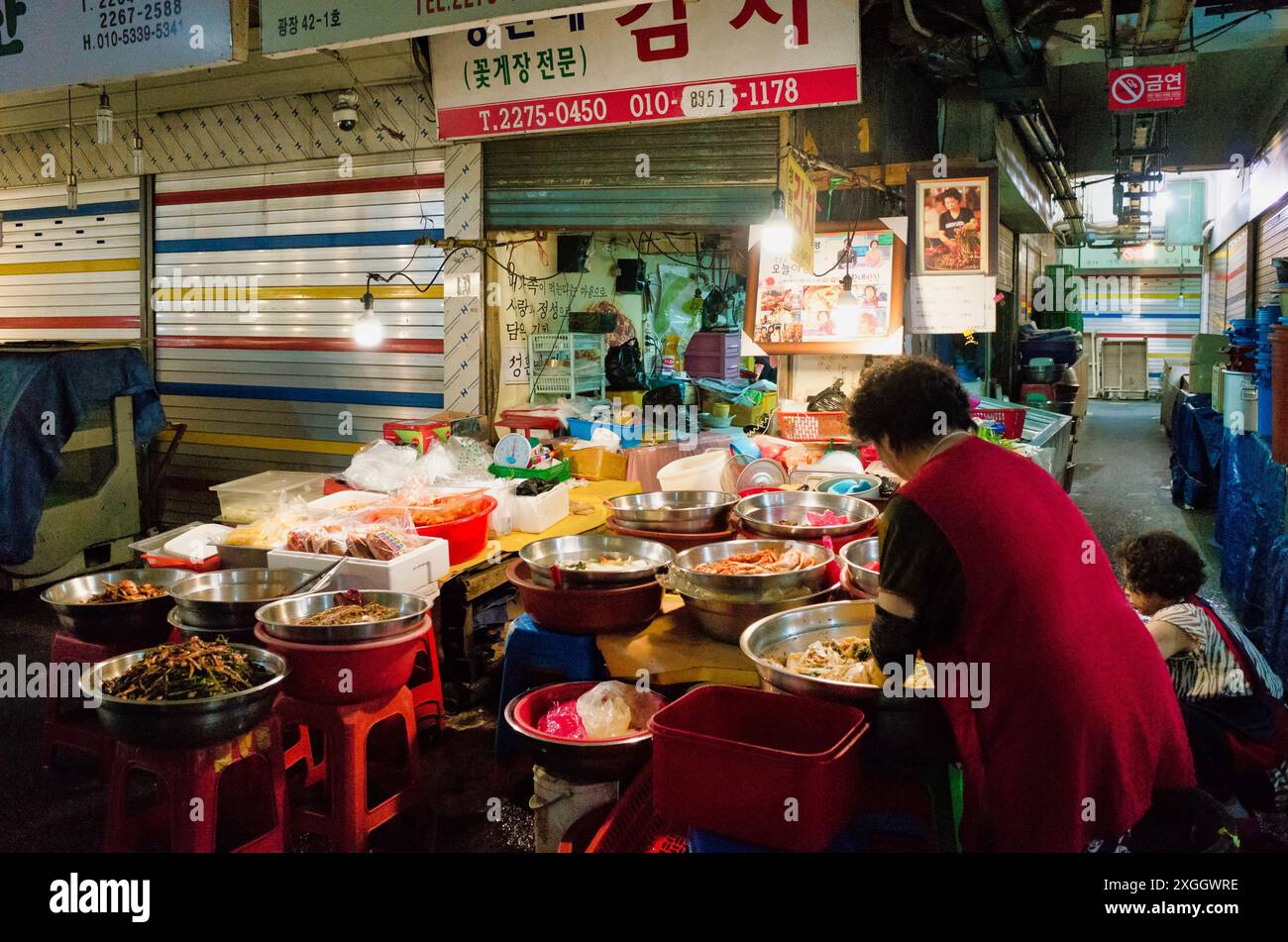 Vibrant Korean market stall with various side dishes and a vendor in ...