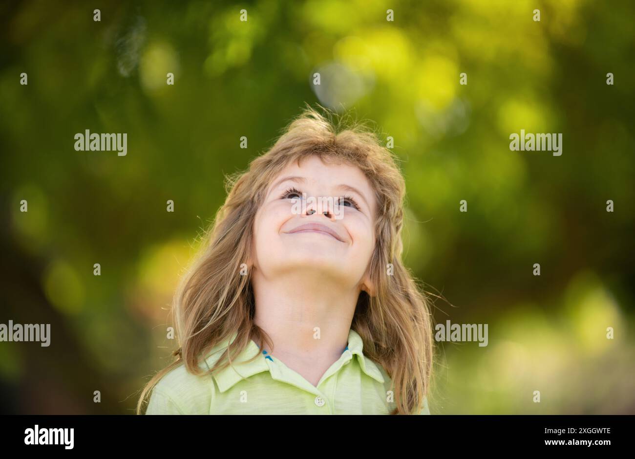 Portrait of happy kid looking up outdoors. Emotional little boy ...