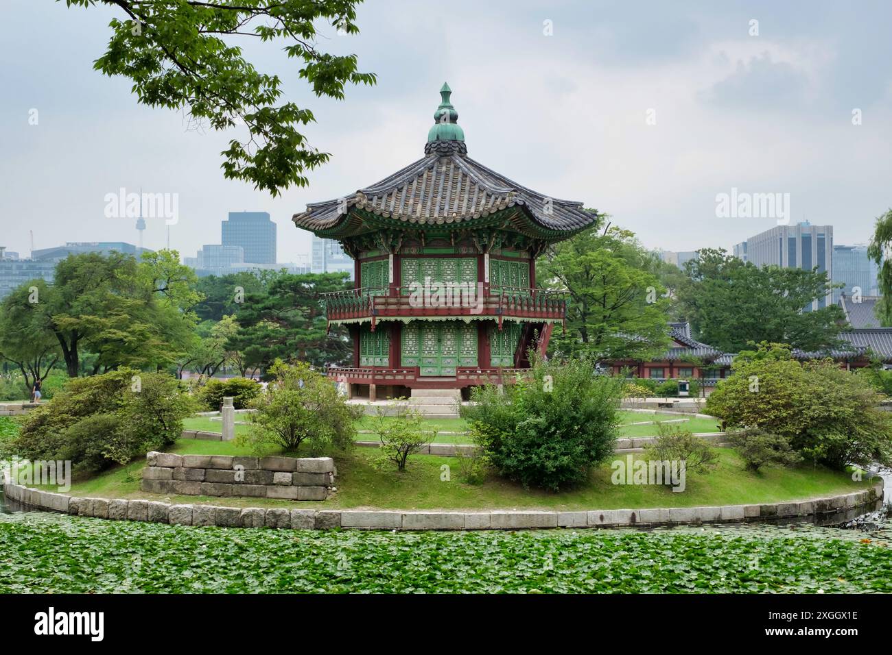 Traditional Korean pavilion surrounded by lush greenery, modern Seoul ...