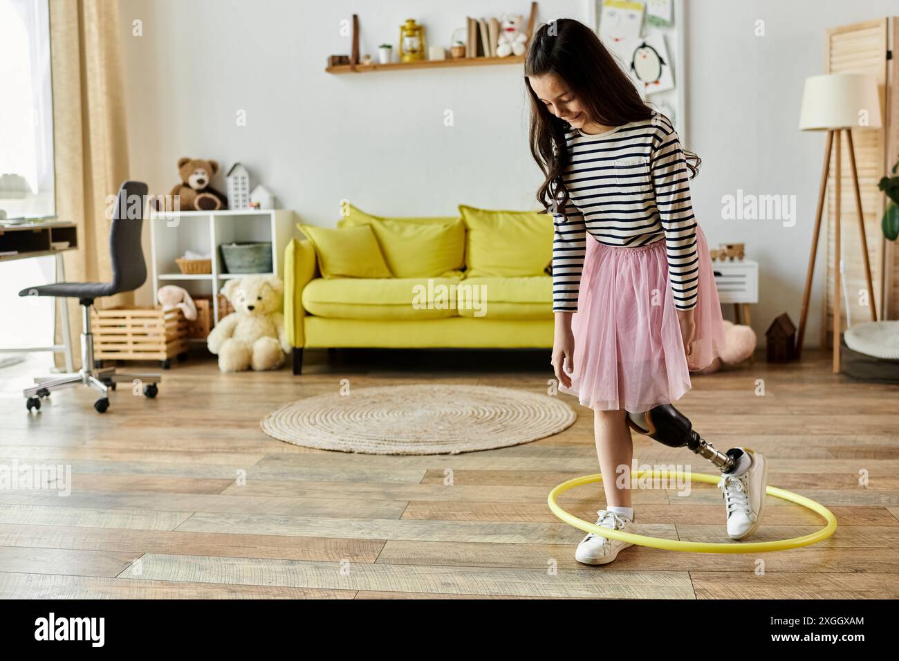 A young girl with a prosthetic leg smiles as she plays with a hula hoop ...