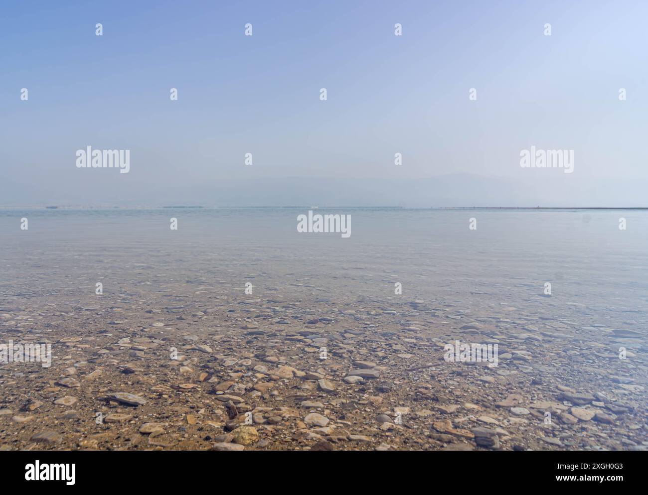 The beautiful stone beach of the Dead Sea, Israel, with the blue salty water at the resort of ...