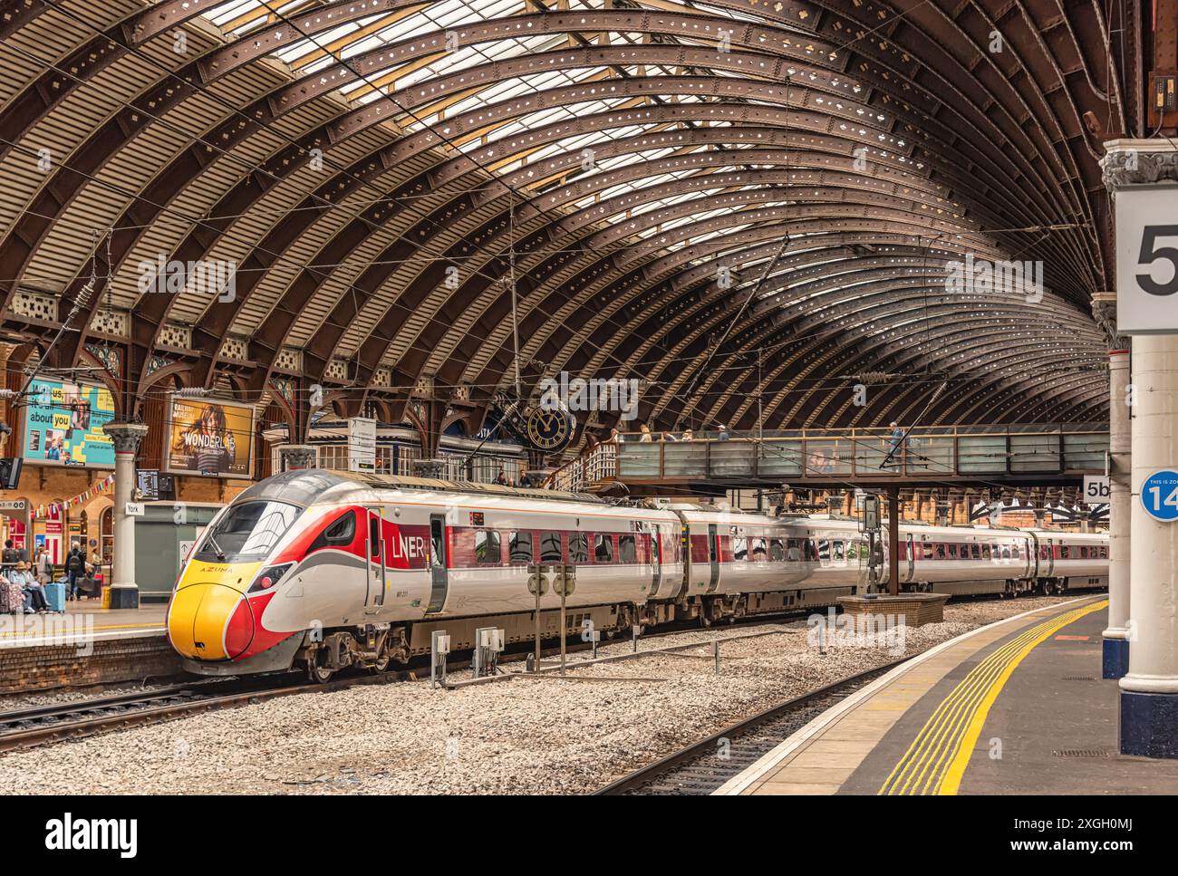 A train travels past a railway station platform. There is a historic ...