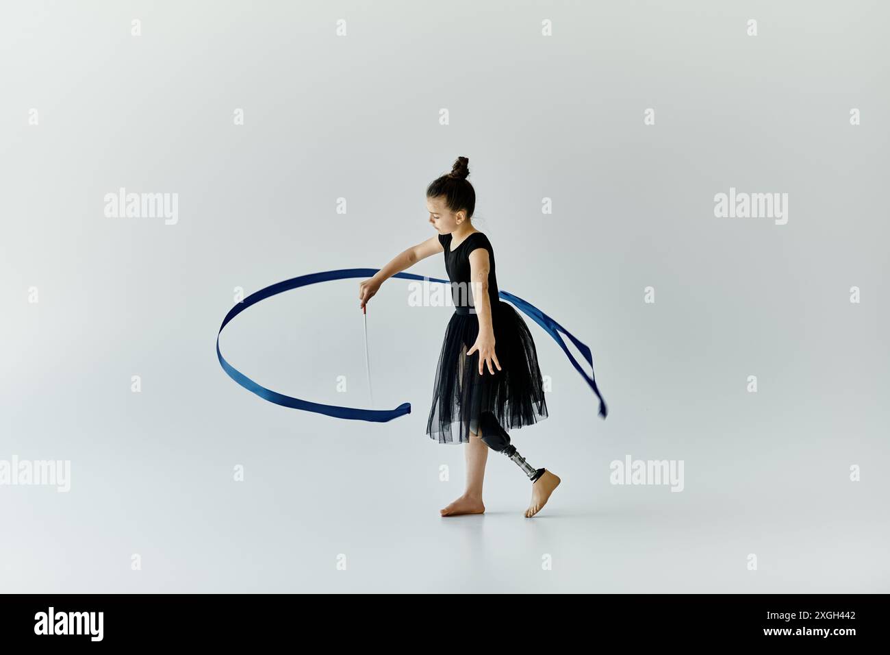 A young girl with a prosthetic leg performs a graceful ribbon routine ...