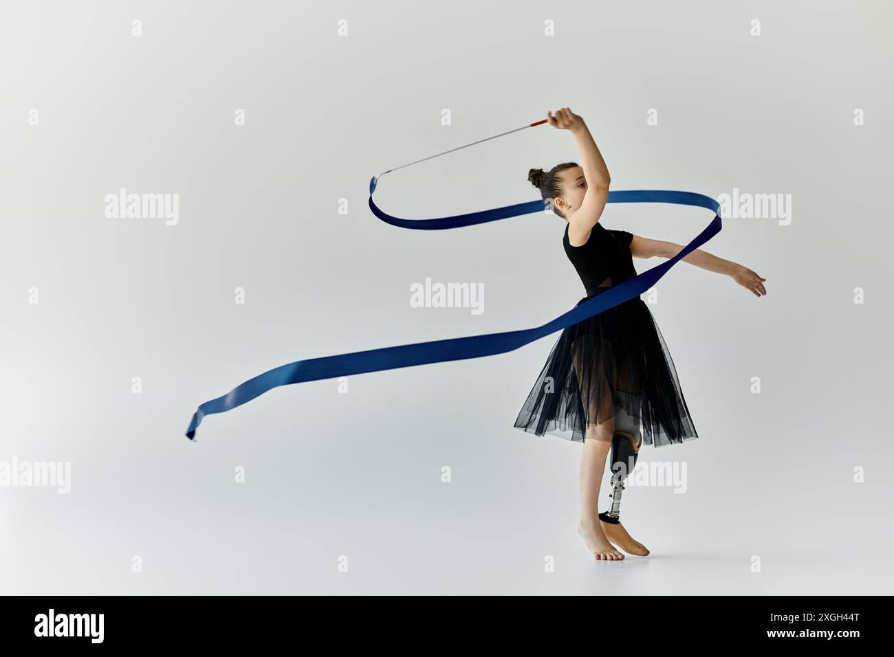 A young girl with a prosthetic leg gracefully performs a ribbon routine ...
