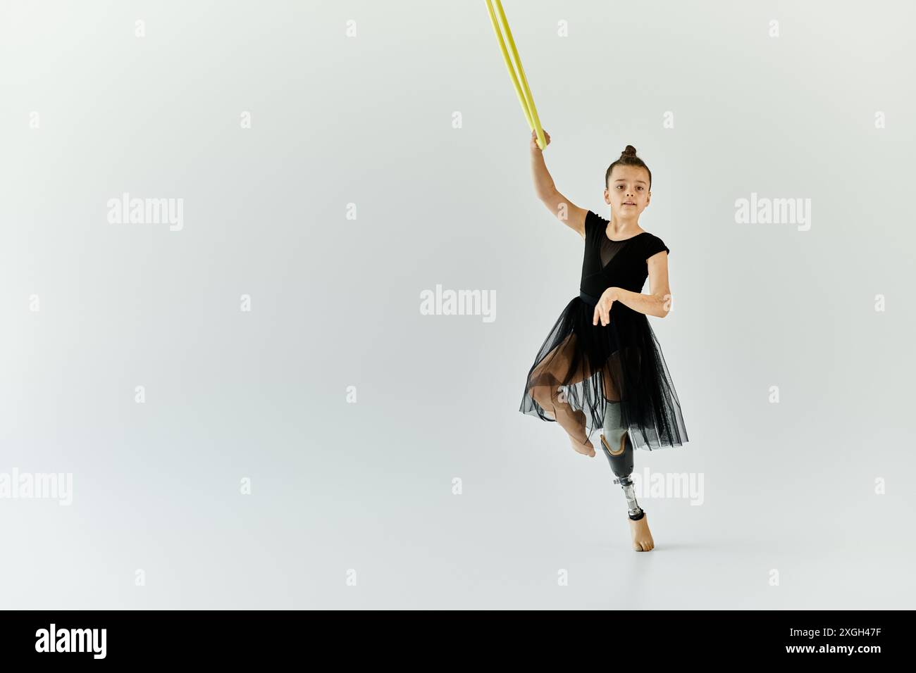 A young girl with a prosthetic leg performs a graceful gymnastic pose ...