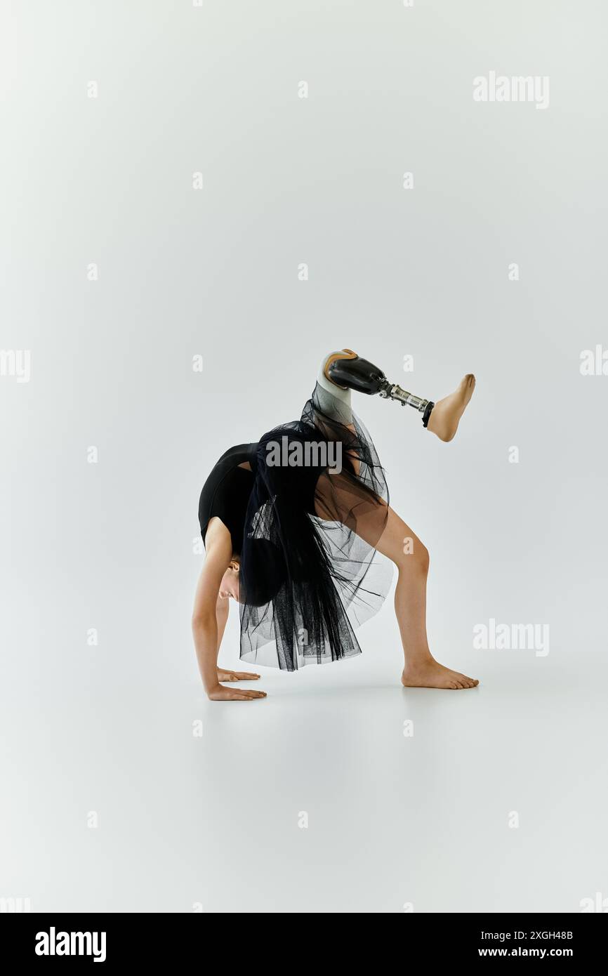 A young girl with a prosthetic leg performs a gymnastics pose ...