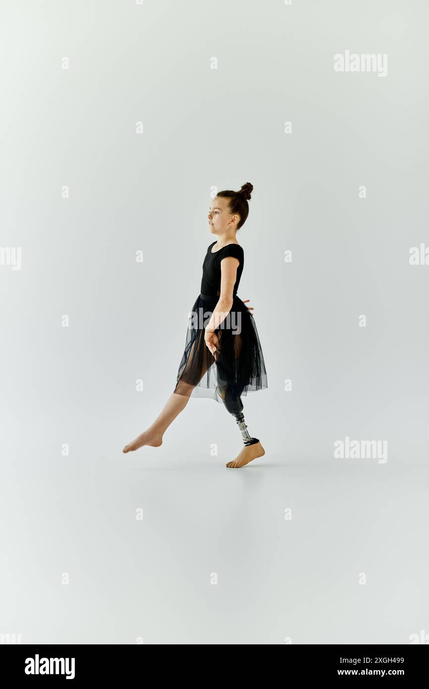 A young girl with a prosthetic leg performs a graceful step in a ballet ...
