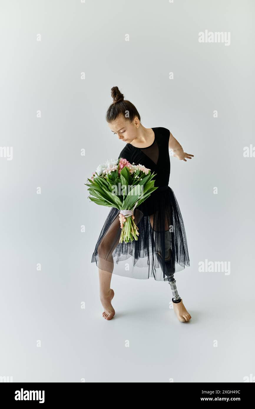 A young gymnast with a prosthetic leg poses gracefully while holding a ...