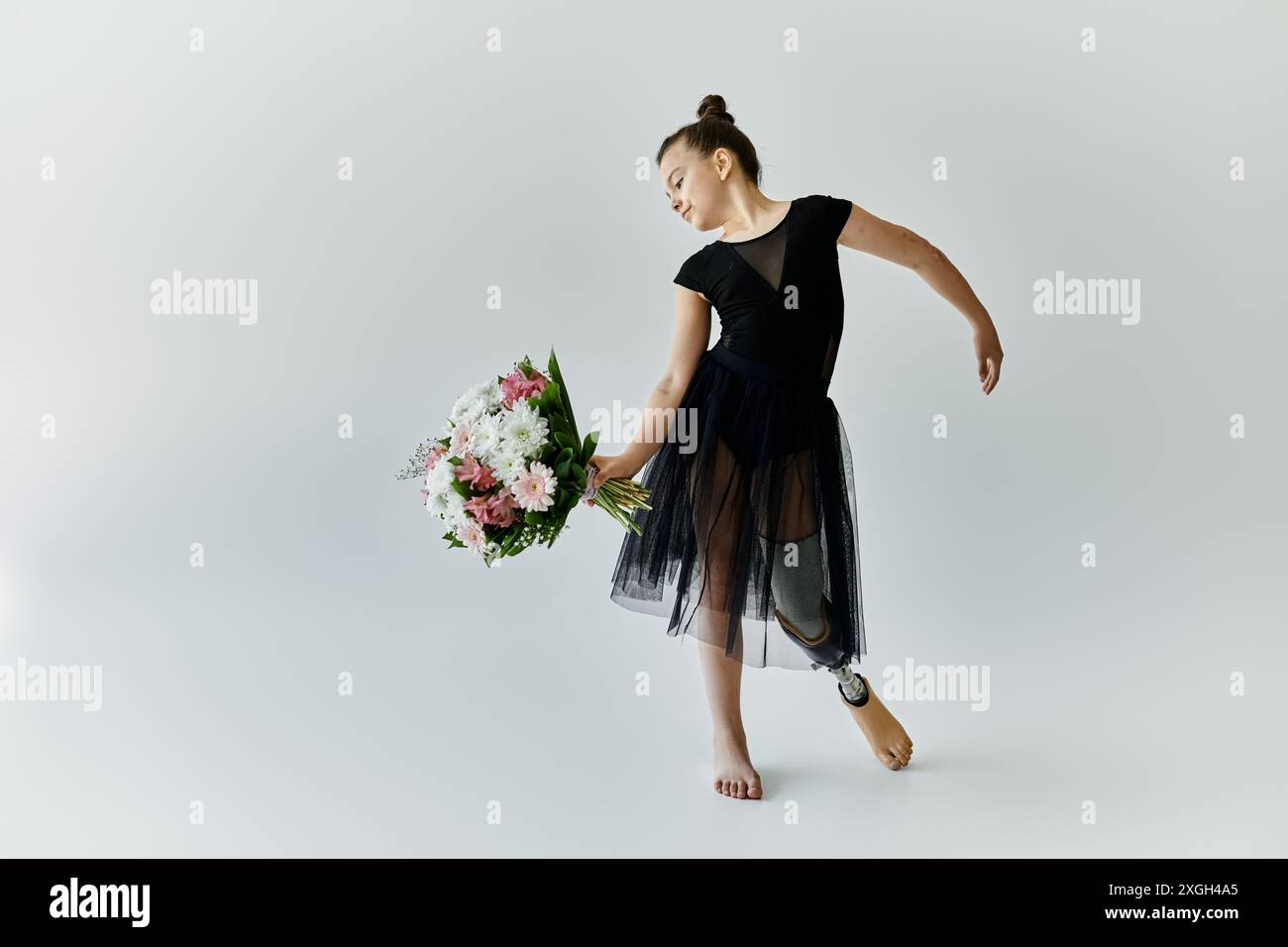 A young girl with a prosthetic leg performs a graceful dance move while ...