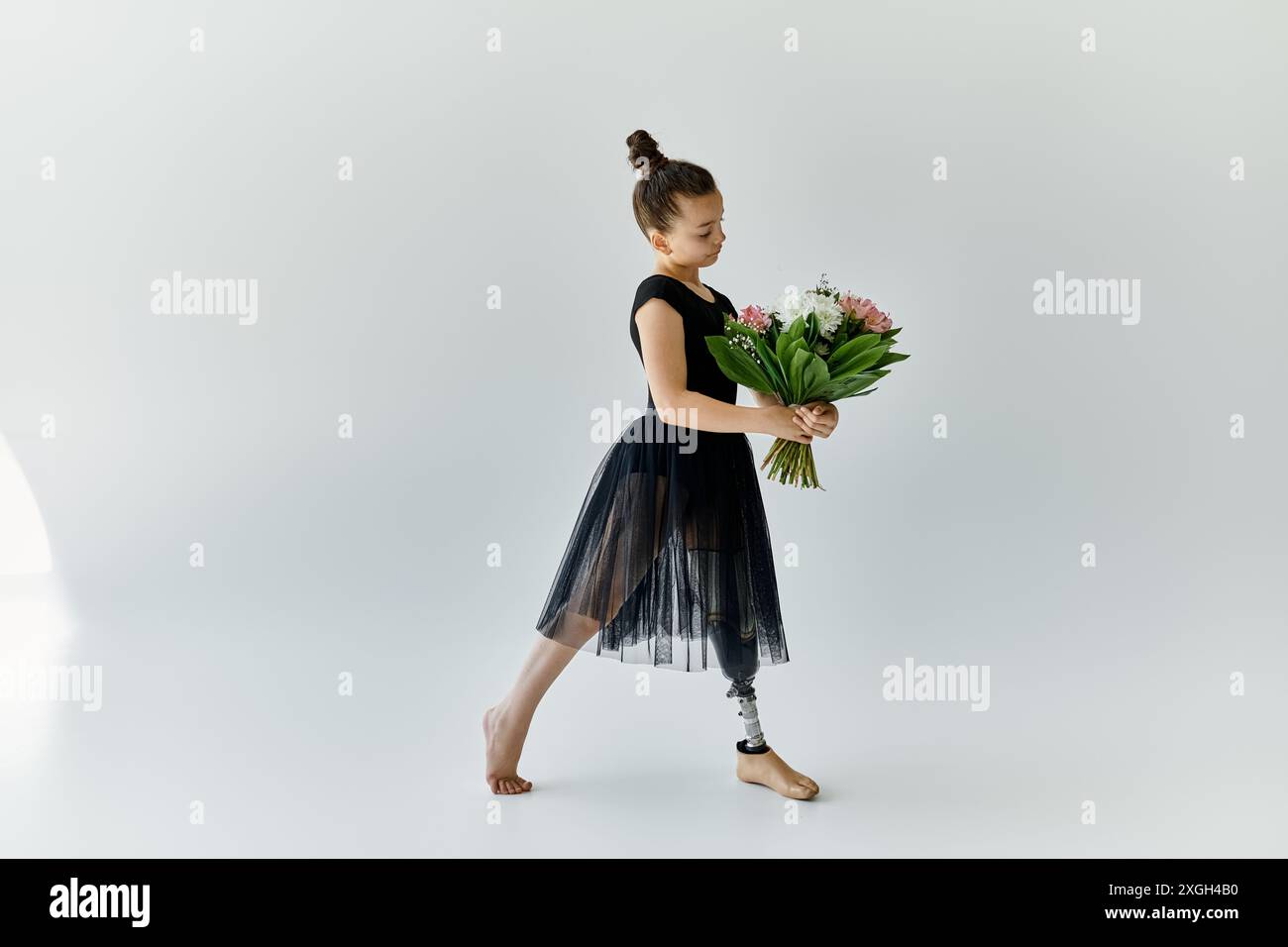 A young girl with a prosthetic leg poses in a gymnastics studio ...
