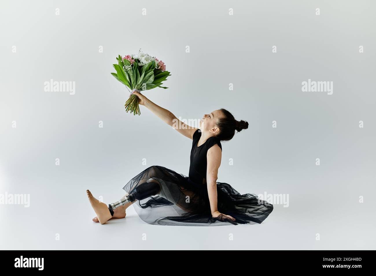 A young girl with a prosthetic leg performs a graceful gymnastic pose ...