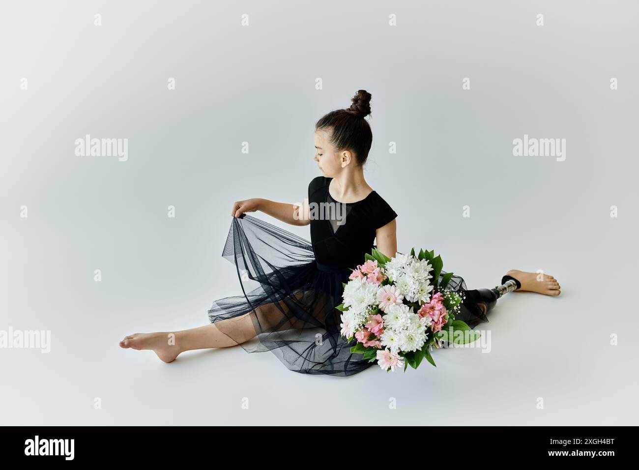 A young girl with a prosthetic leg performs a gymnastics split while ...