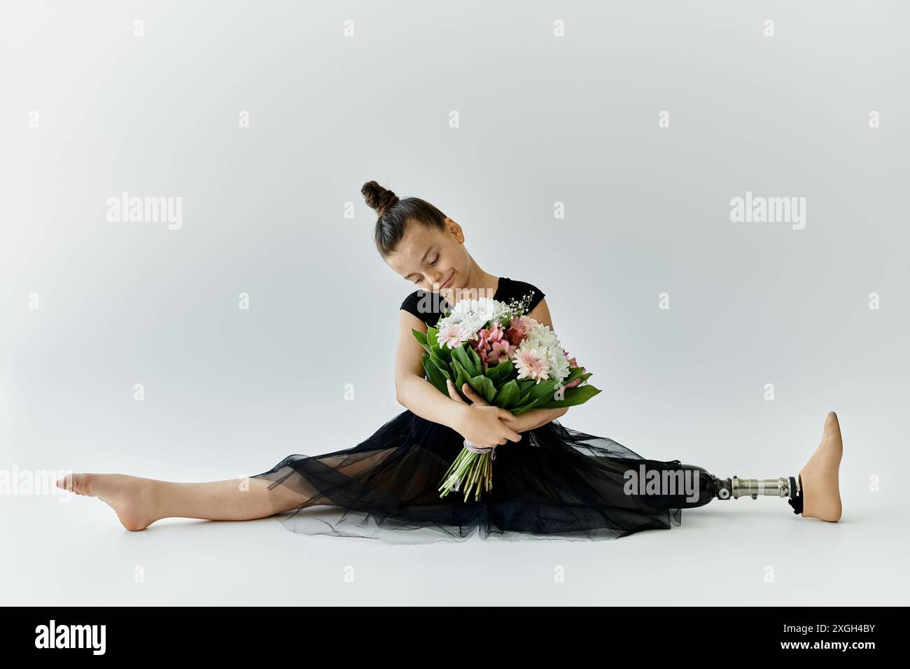 A young girl with a prosthetic leg gracefully performs a split while ...