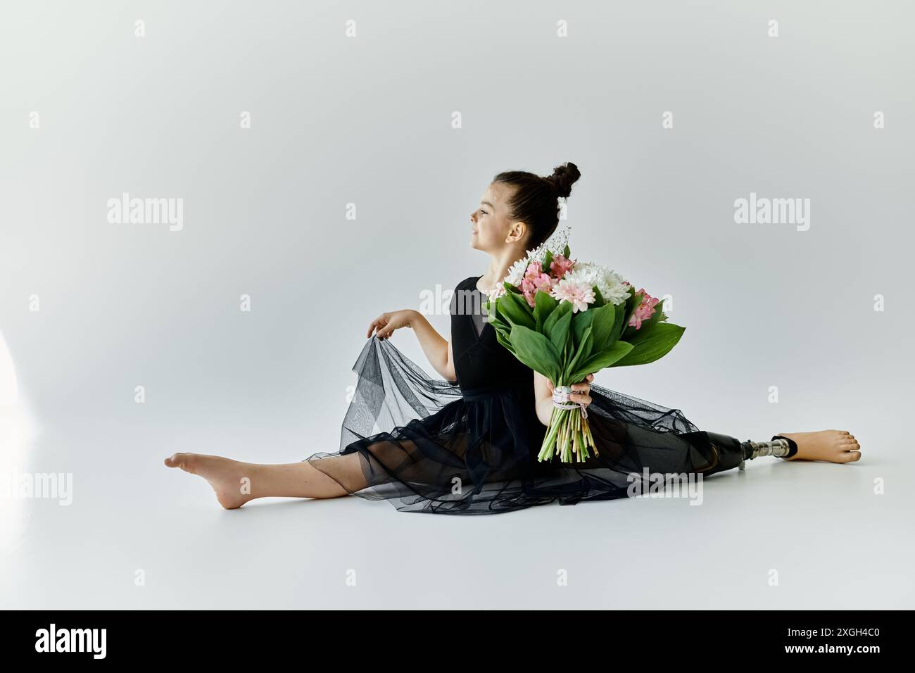 A young girl with a prosthetic leg performs a gymnastics pose ...