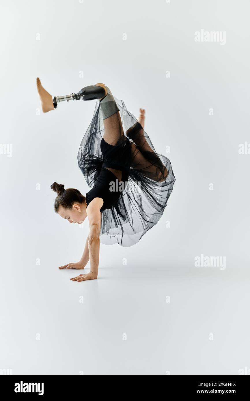 A young girl with a prosthetic leg performs a graceful handstand in a ...