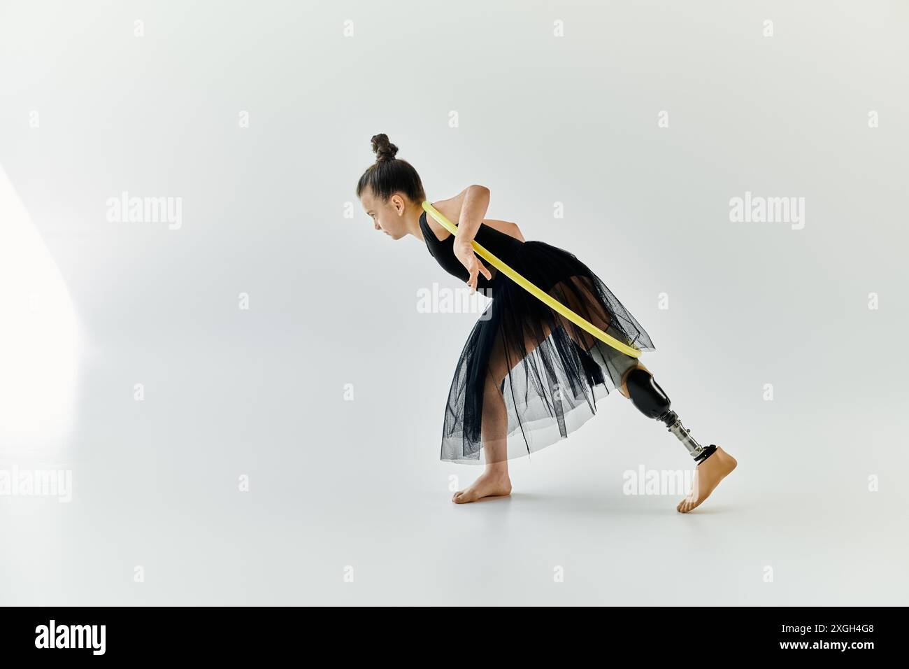 A young girl with a prosthetic leg performs a gymnastic move with a ...