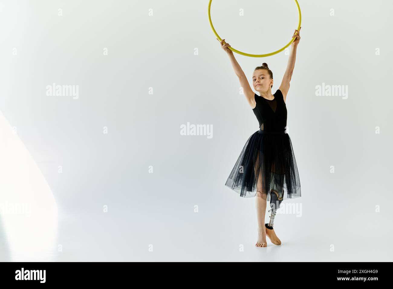 A young girl with a prosthetic leg performs a graceful gymnastic pose ...