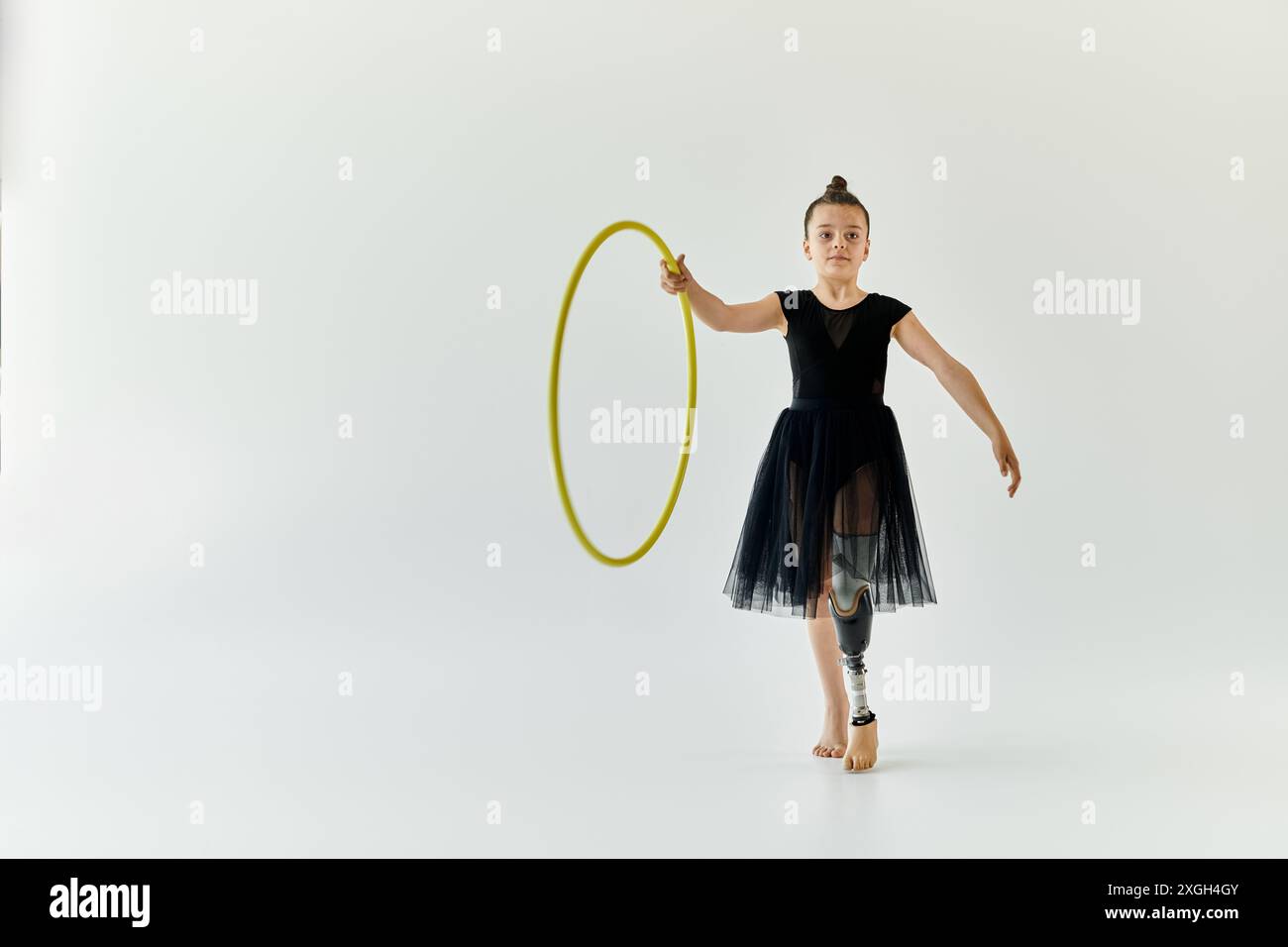 A young girl with a prosthetic leg performs a gymnastics routine with a ...