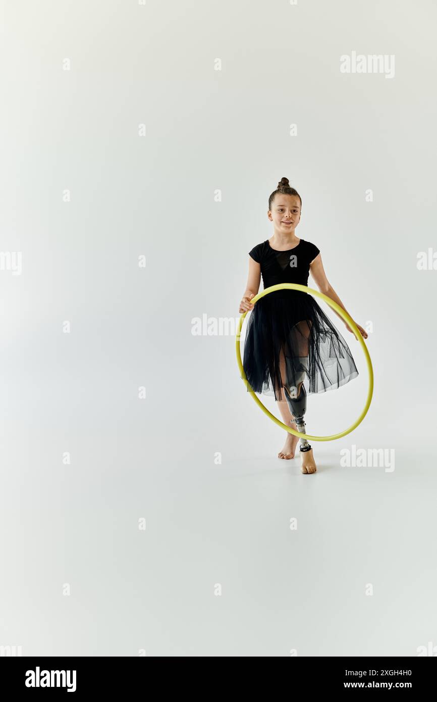 A young girl with a prosthetic leg is spinning a hula hoop in a studio ...