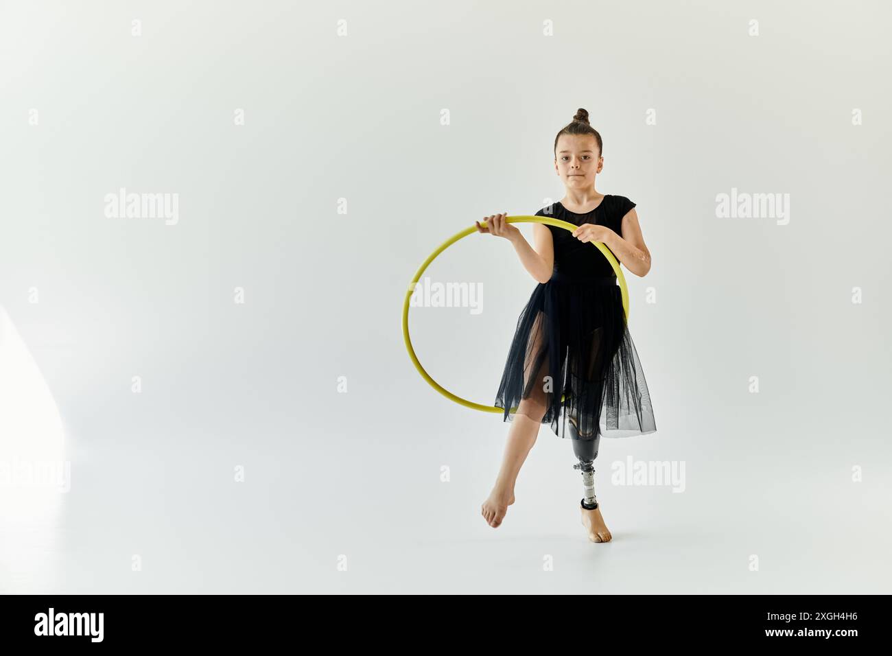 A young girl with a prosthetic leg performs gymnastics with a hula hoop ...