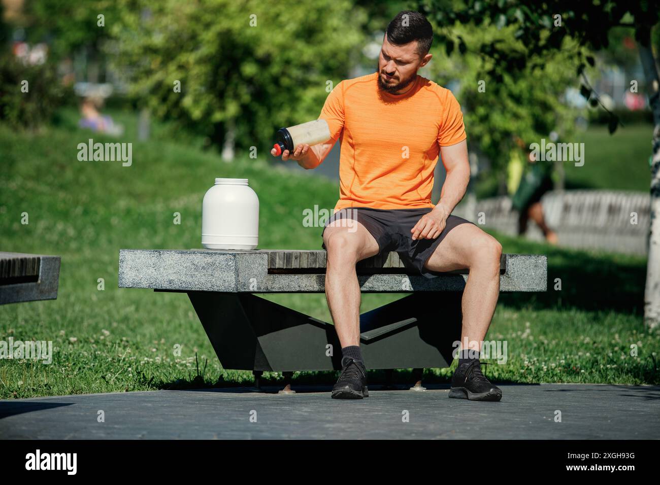 Athletic man wearing orange and black sportswear sitting on bench ...
