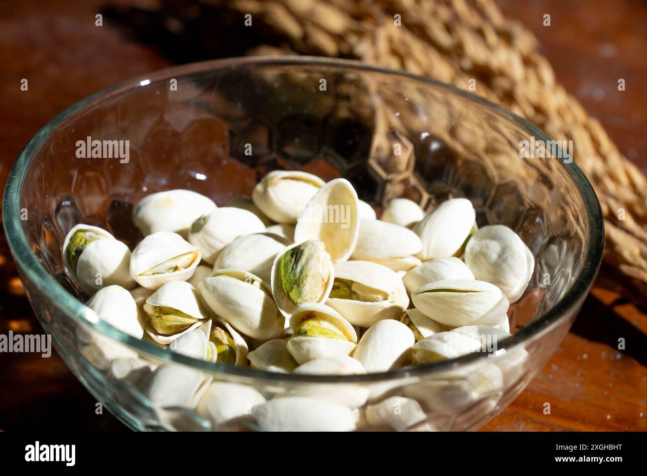 Pistachio nuts in white glass bowl isolated on brown table background ...