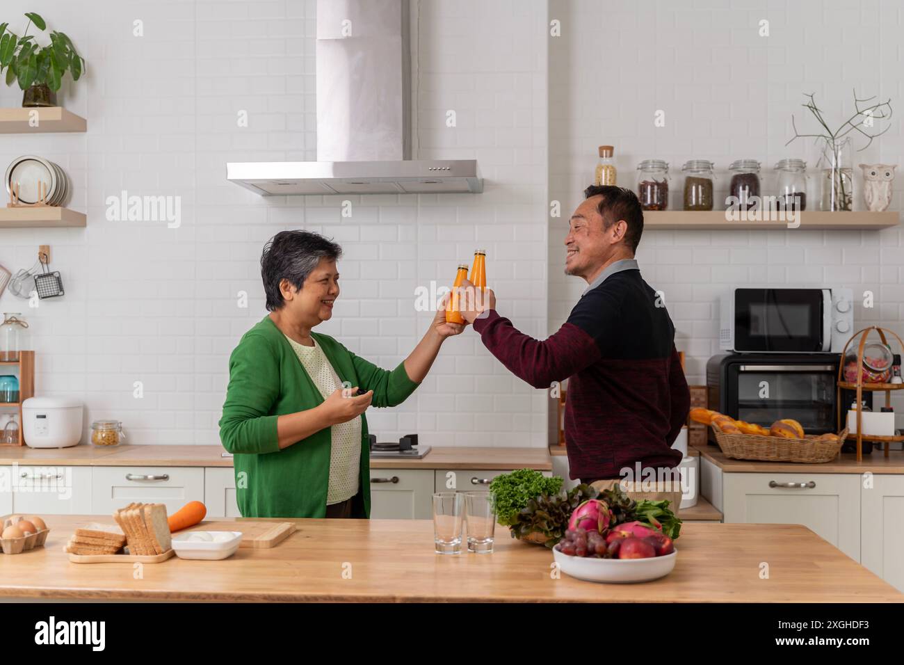 Lively middle-aged family couple dancing to disco music in the kitchen ...