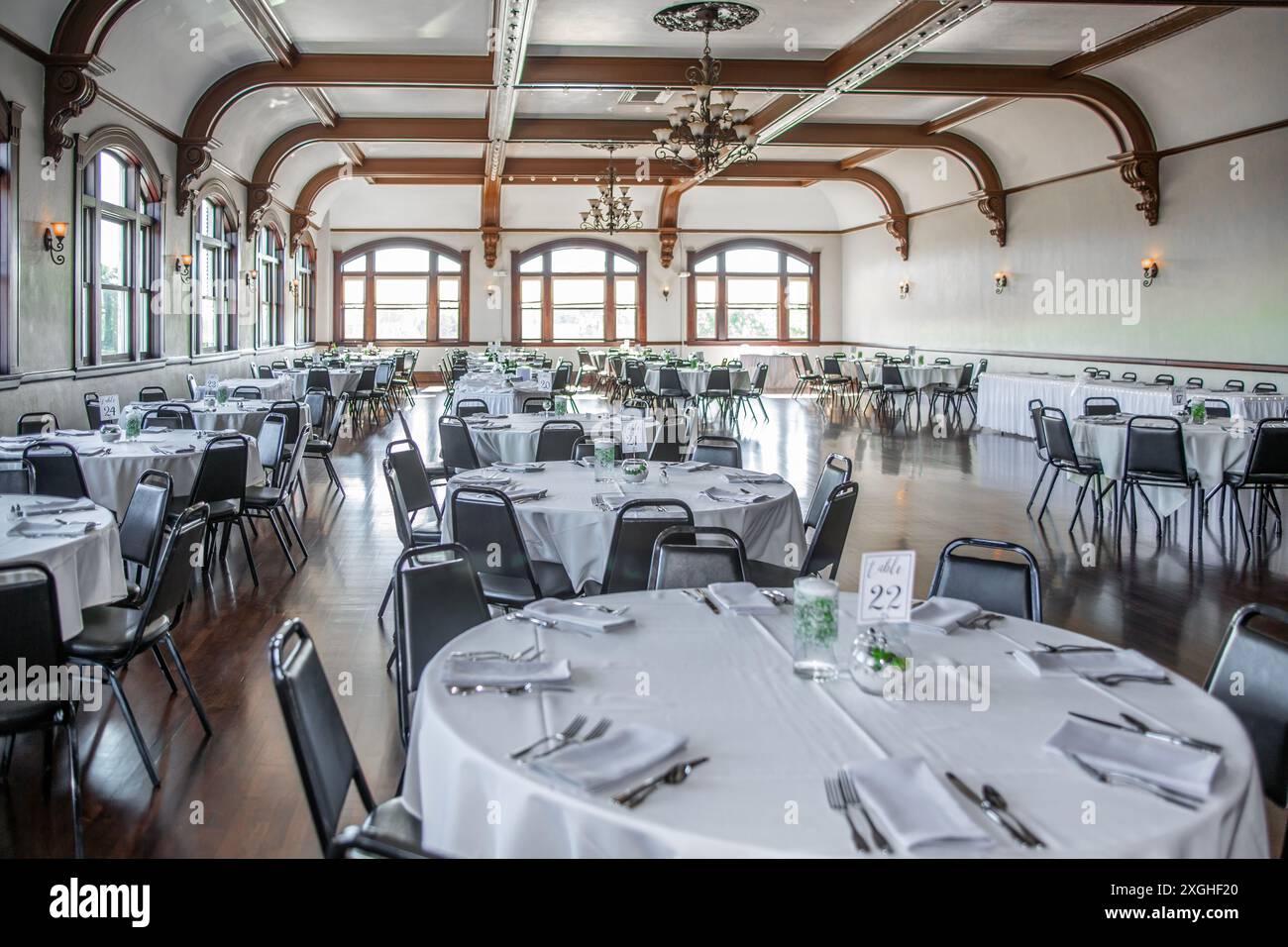 An elegant banquet hall with round tables set for a wedding event with ...