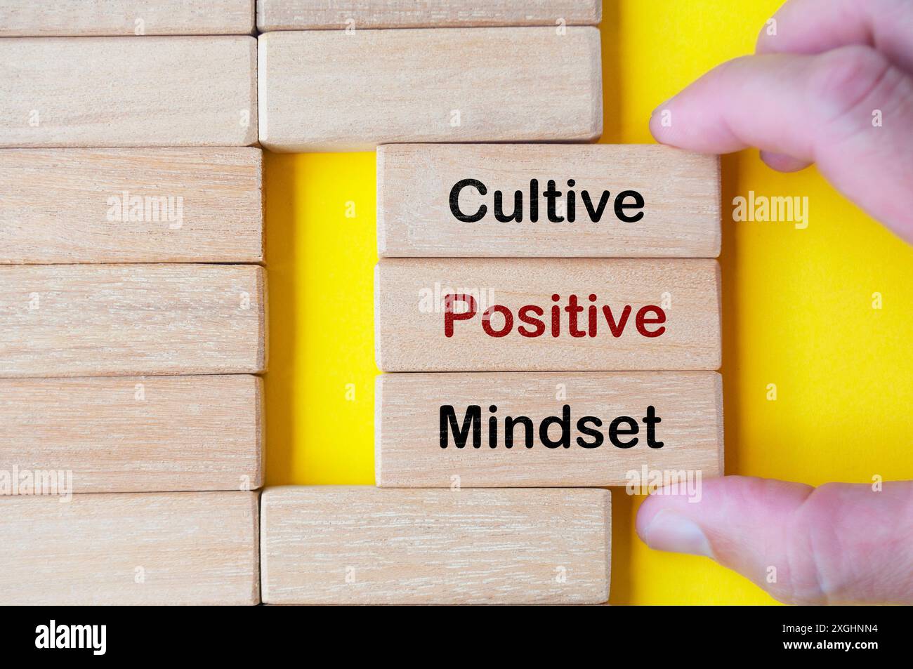 Hand pulling wooden blocks with Cultivate Positive Mindset text on ...