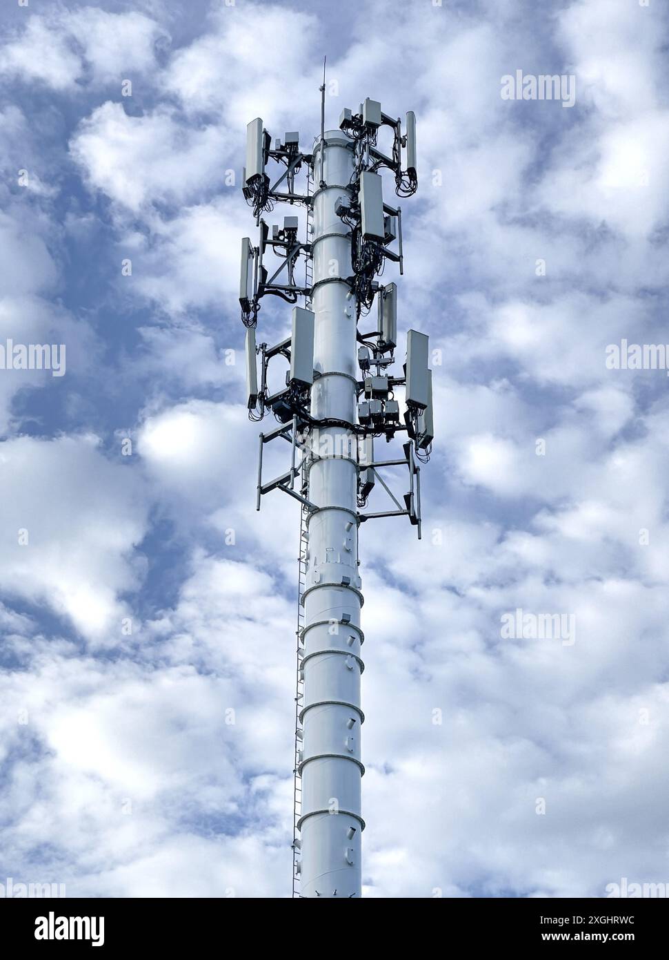 Cell phone tower equipped with multiple antennas and transmitters under blue sky Stock Photo - Alamy