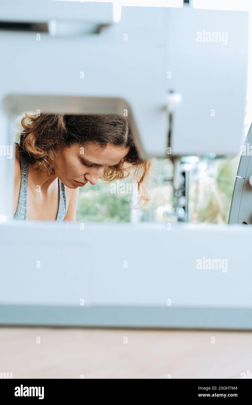 Vertical portrait of a woman tailor sits against background of a sewing ...
