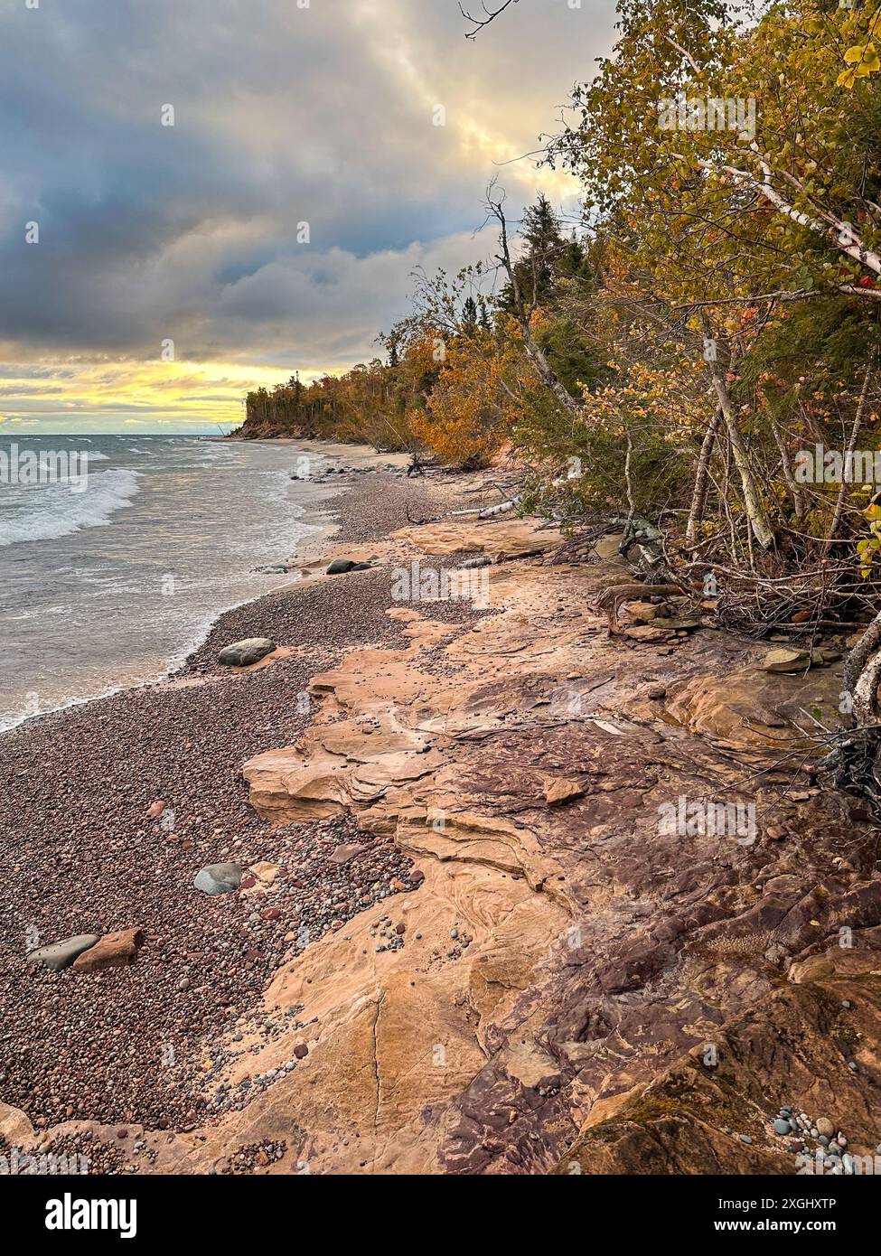 Beautiful lakeshore landscape, with trees and rocks at the water's edge ...