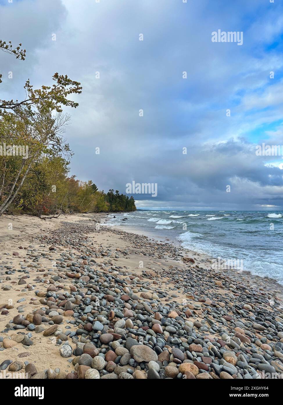 Beautiful lakeshore landscape, with trees and rocks at the water's edge ...