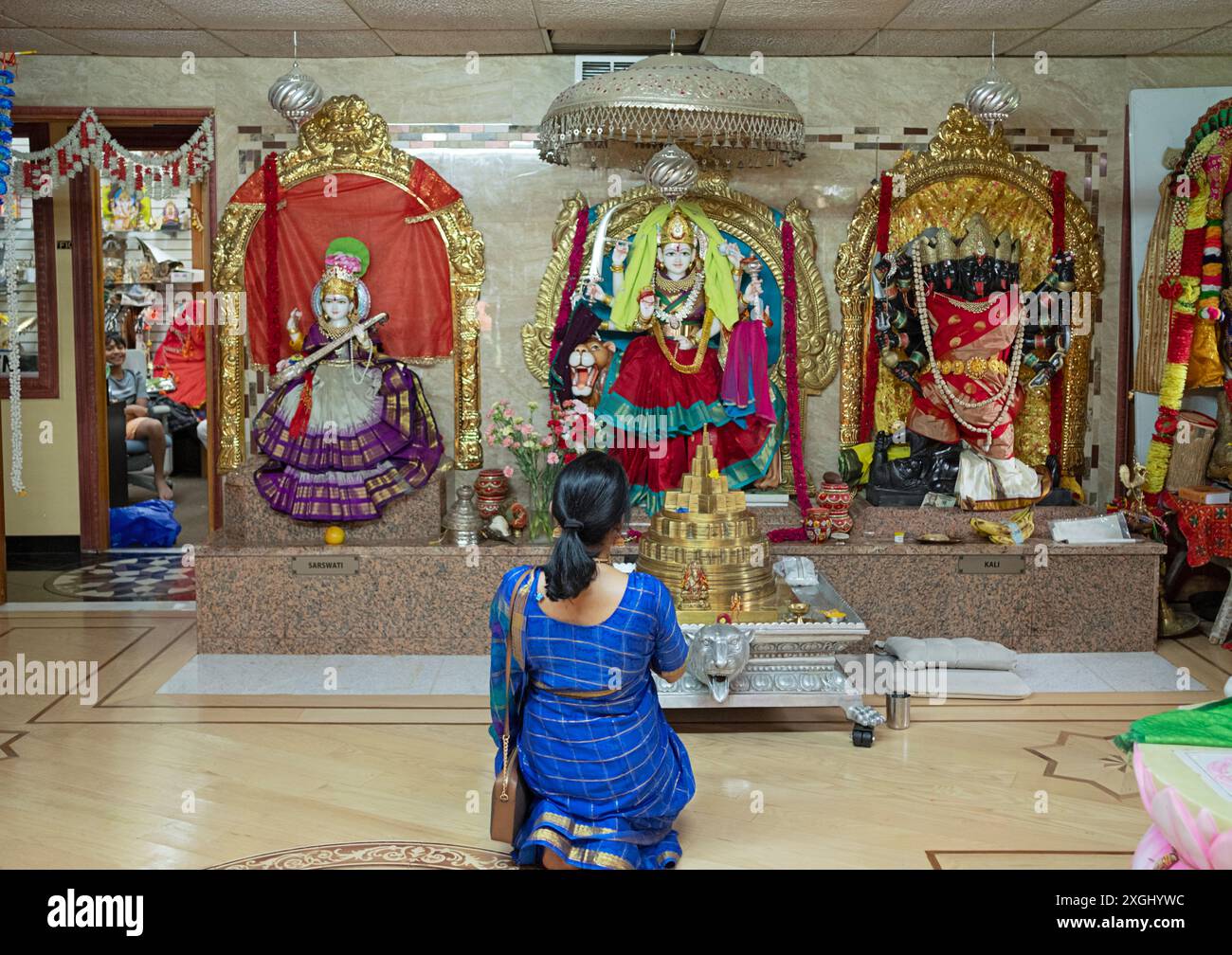 An unidentified Hindu woman prays at a temple. The deities, from left ...
