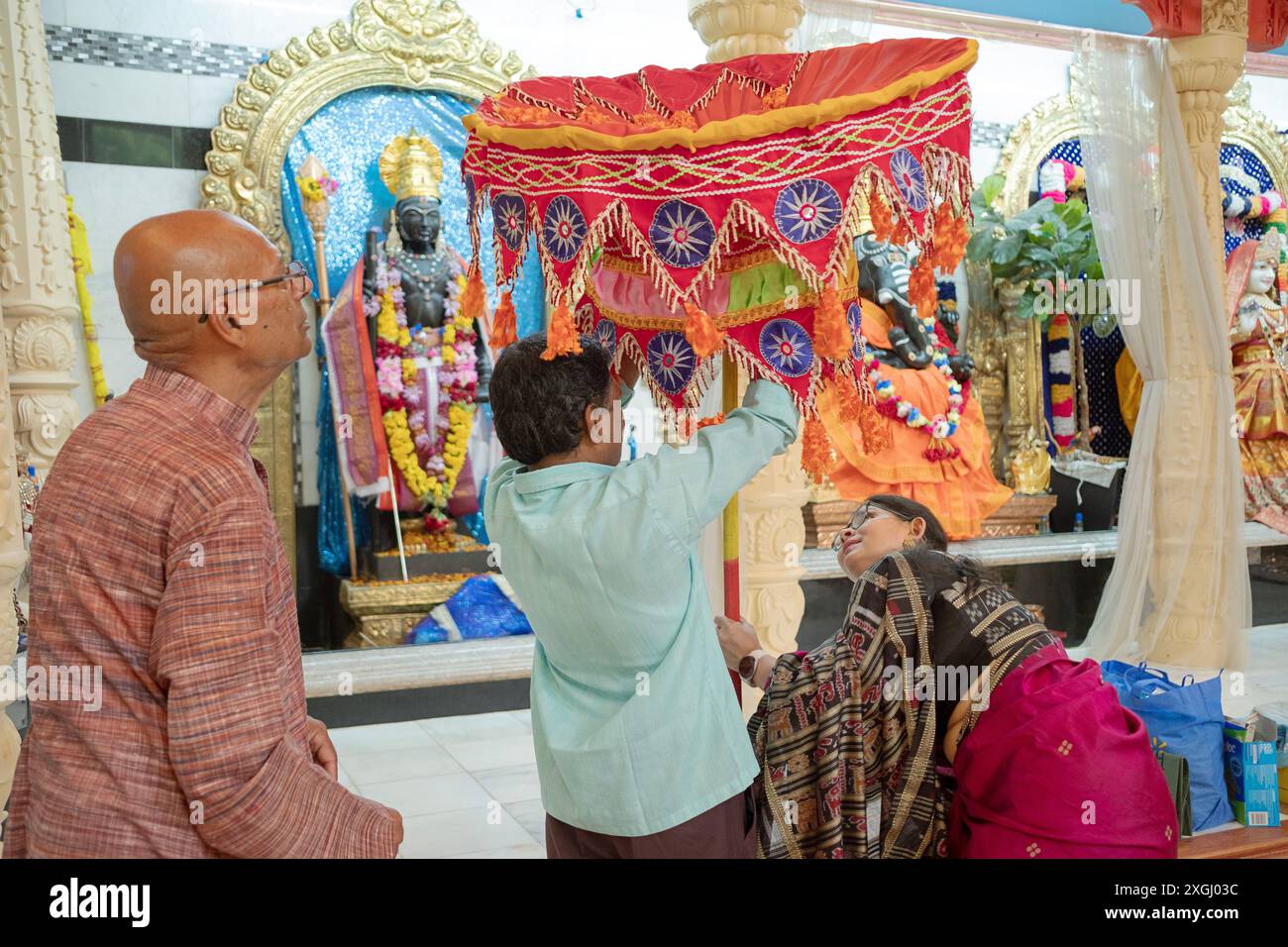 At the Wilton Hindu temple, 3 devotees prepare a colorful ornament to ...