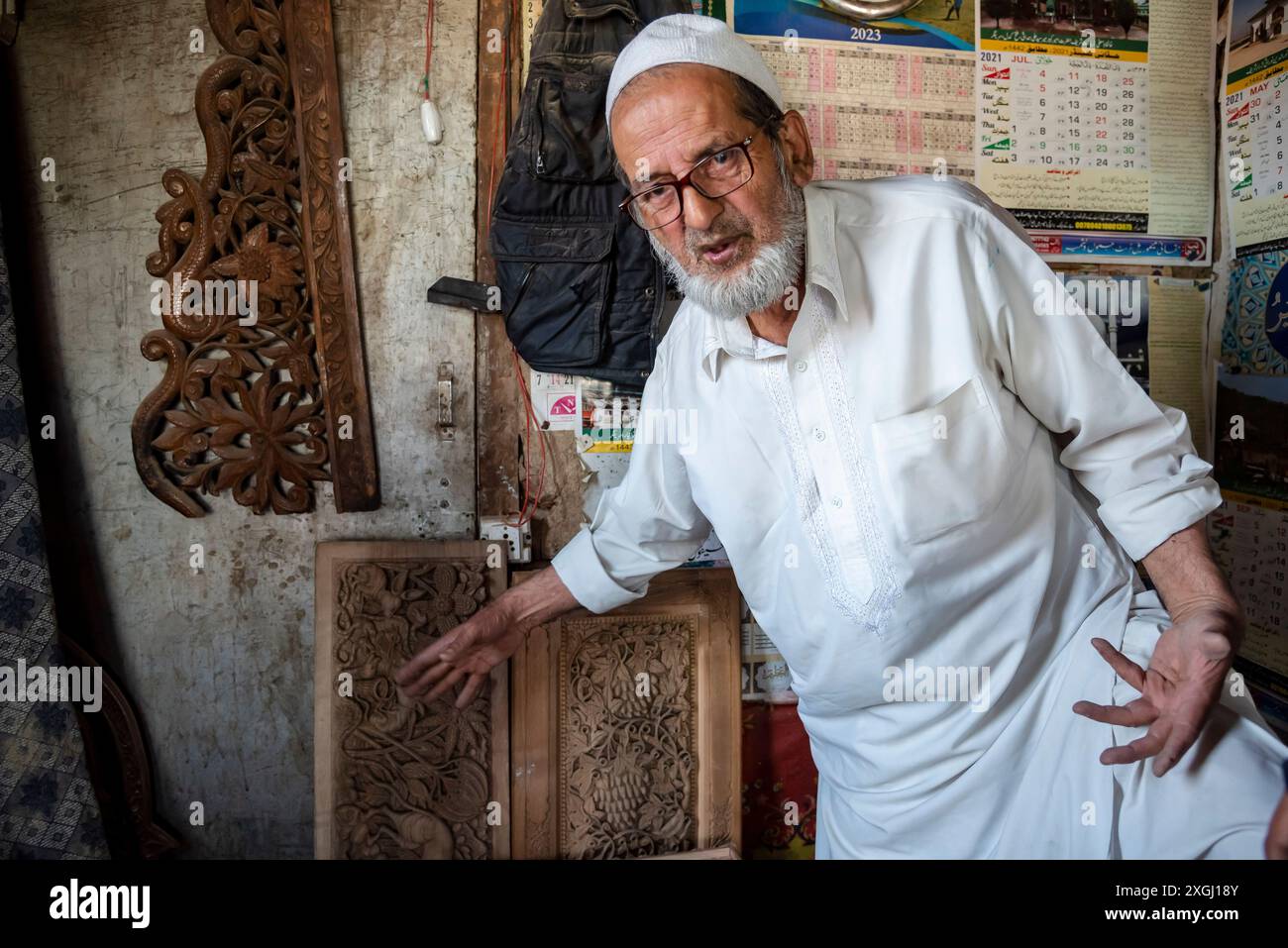 Master artisan Ghulam Nabi Zarger displays his crafted artworks on the walnut wood surface at ...