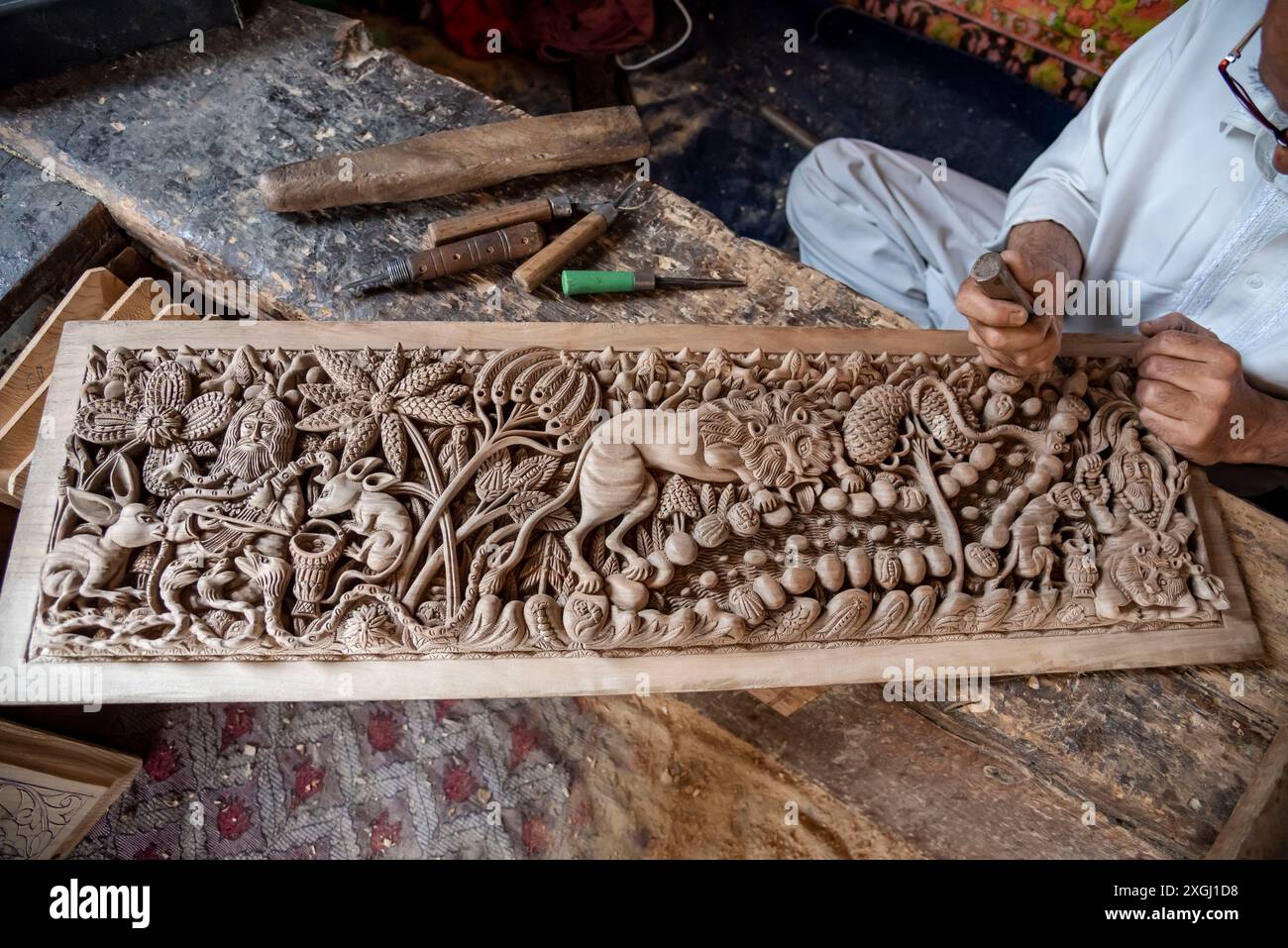 A master artisan is seen crafting designs on a wooden piece at his ...
