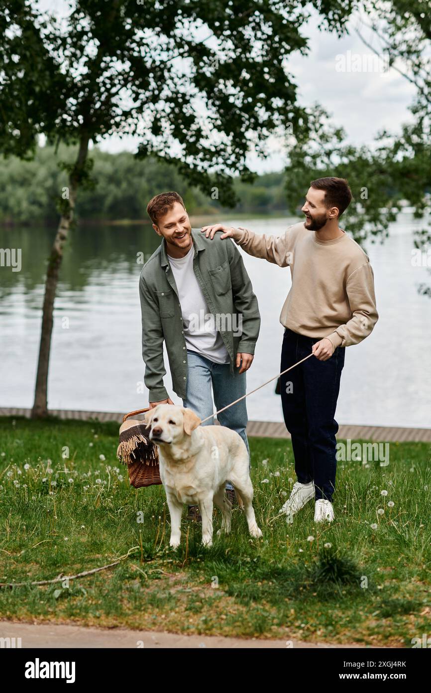 Two bearded men are enjoying a picnic in the park with their labrador ...