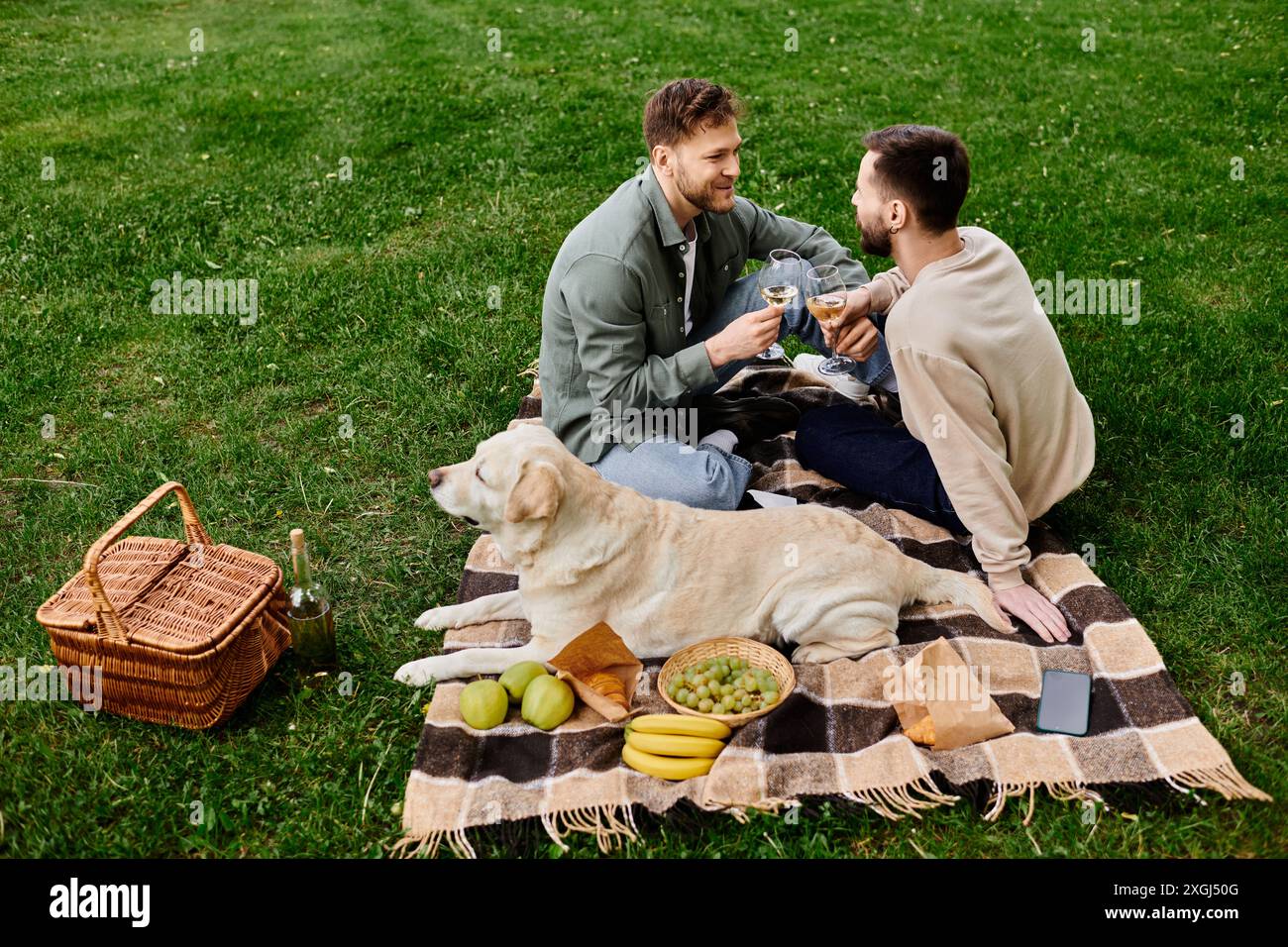 A bearded gay couple enjoys a picnic in a grassy park with their ...