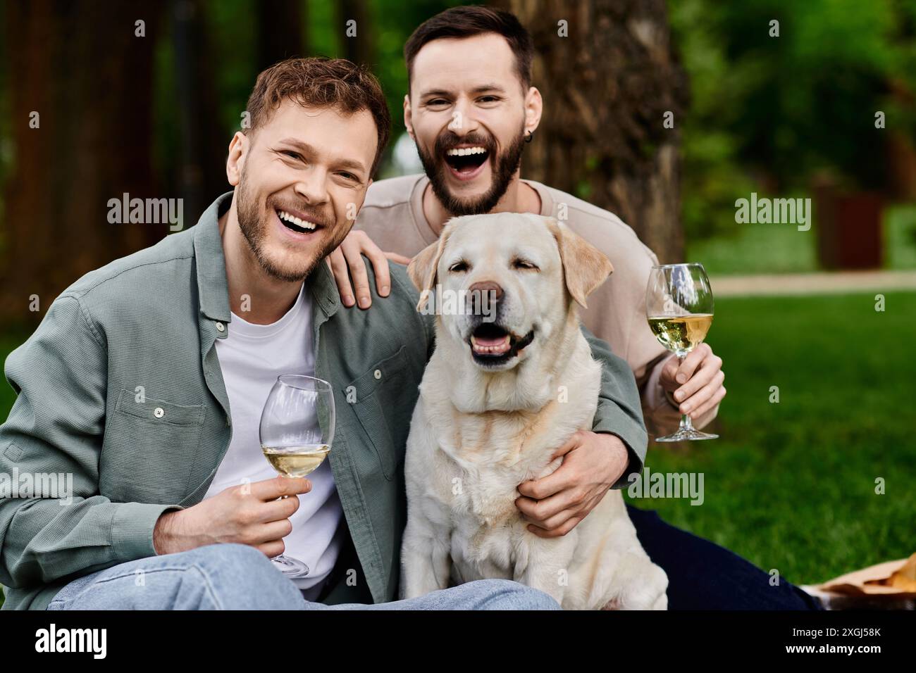 Two bearded men laugh joyfully with their Labrador dog while enjoying a ...