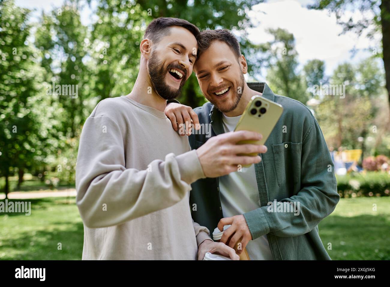 Two bearded gay men laugh together while looking at a smartphone in a ...