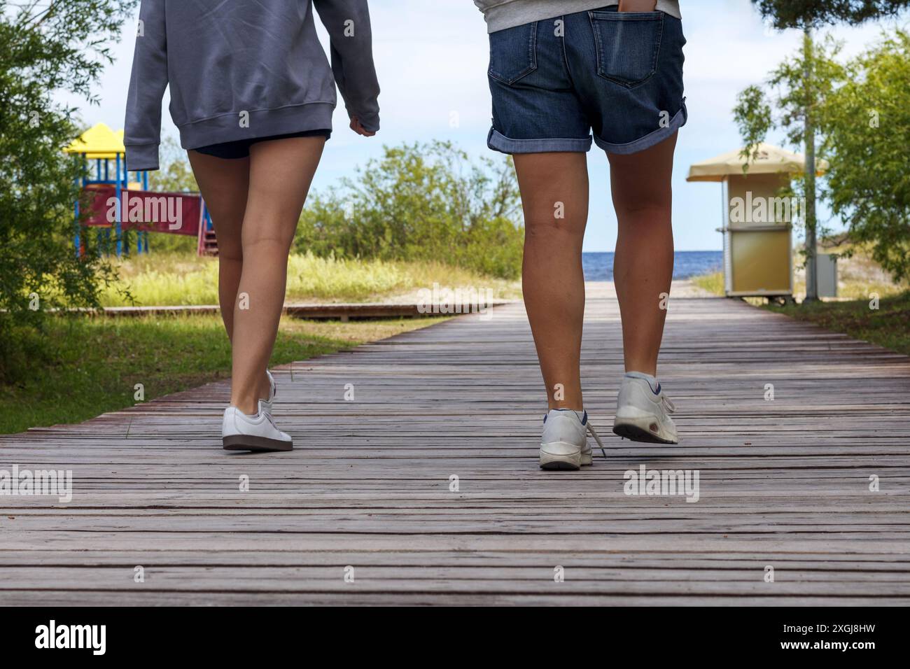legs of a pair of people walking on a wooden plank path along the ...