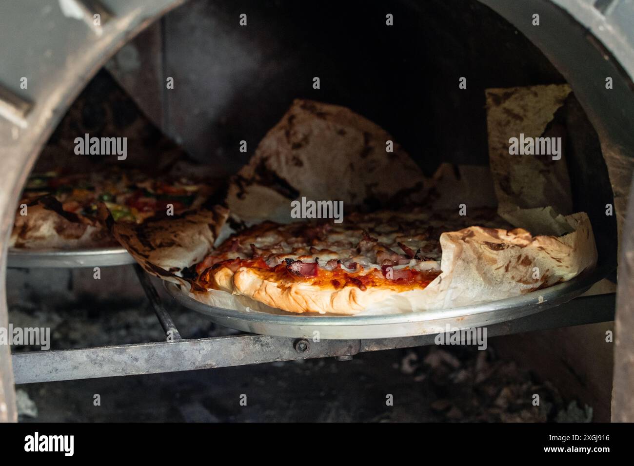 Two pizzas are shown baking inside a traditional stone wood-fired oven, capturing the essence of ...