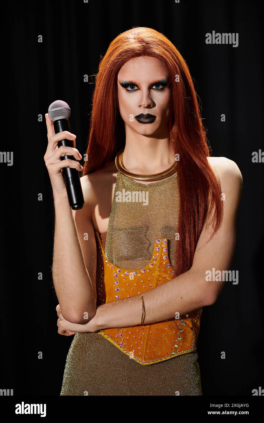 A drag performer poses with a microphone, dressed in a gold and orange ...