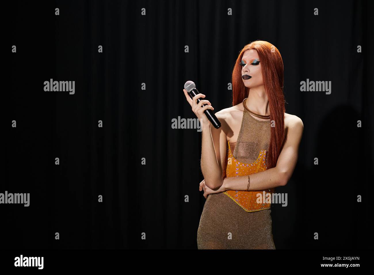 A drag performer with long red hair and a glamorous outfit holds a ...