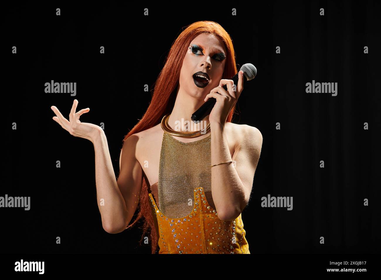 A drag queen with long red hair performs on stage, holding a microphone ...