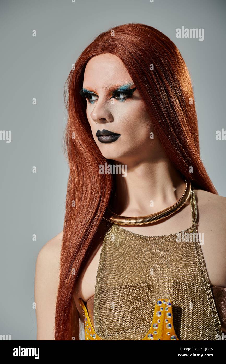 A glamorous drag queen with long red hair poses in a gold mesh top ...