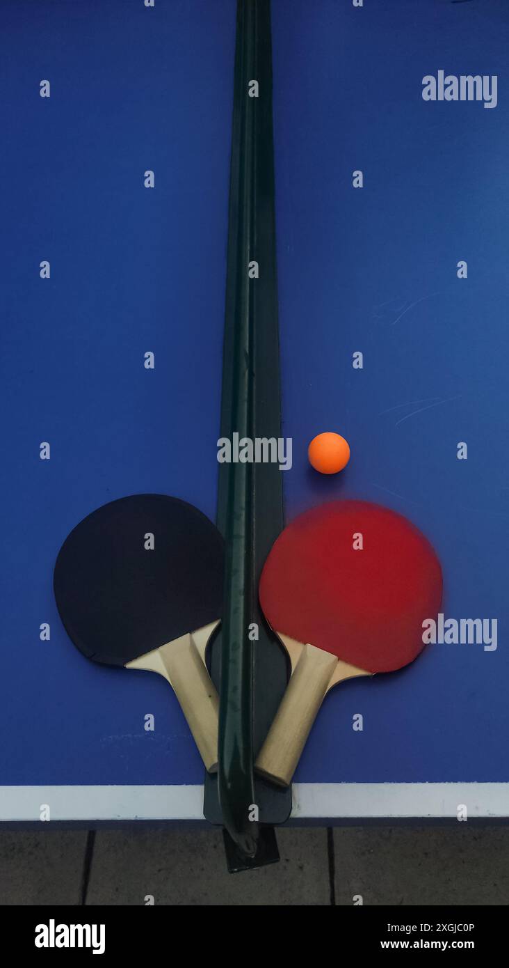 Two ping pong paddles and a ball on a blue table. Vertical mobile photo ...